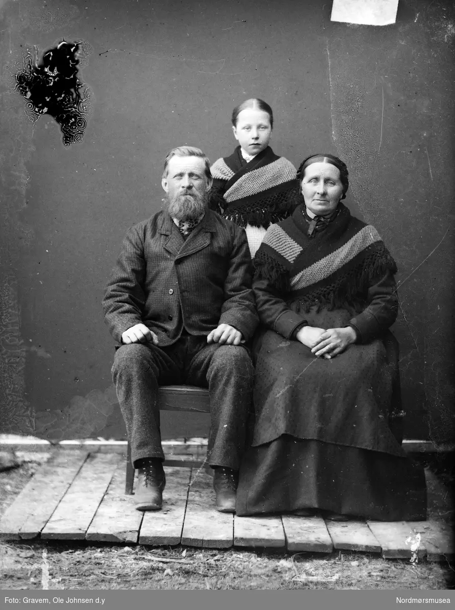Portrett av en sittende mann og dame. Bak står en ung jente. Både jenta ... Portrett av en sittende mann og dame. Bak står en ung jente. Både jenta ...