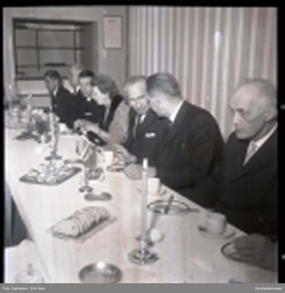 Fotografi av mange menn kledd i dresser med slips og en kvinne som ...