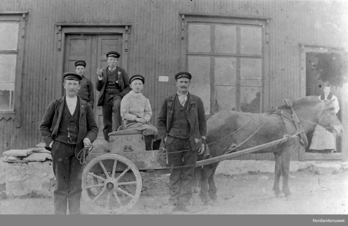 2 menn og 3 gutter rundt en hest med vogn (en av guttene sitter i vogna) foran meieriet i ...