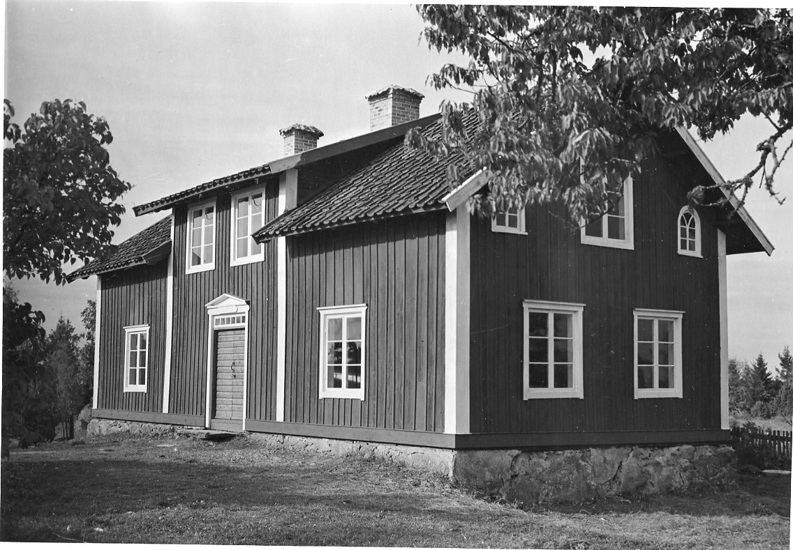En hus med locklistpanel, vita knutar och fönsteromfattningar samt ...
