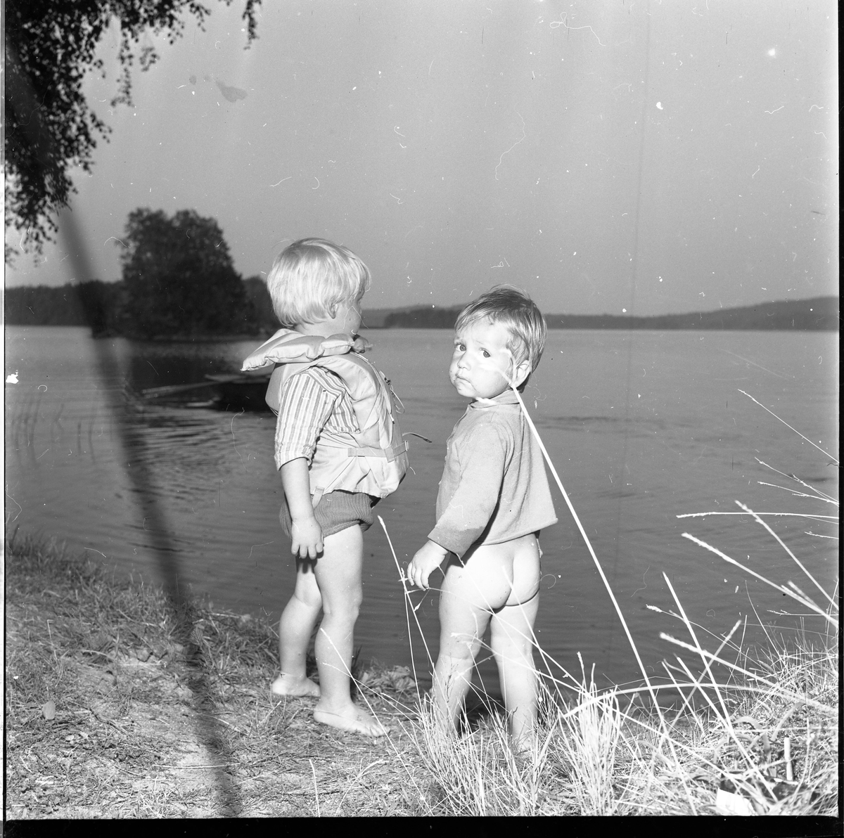 Två små pojkar vid en strand, den ena pojken med flytväst. - Grenna ...