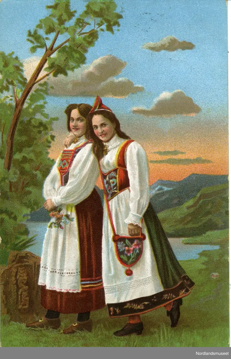 Postkort med bilde av to unge jenter i bunad. Den ene har rød stakk ...