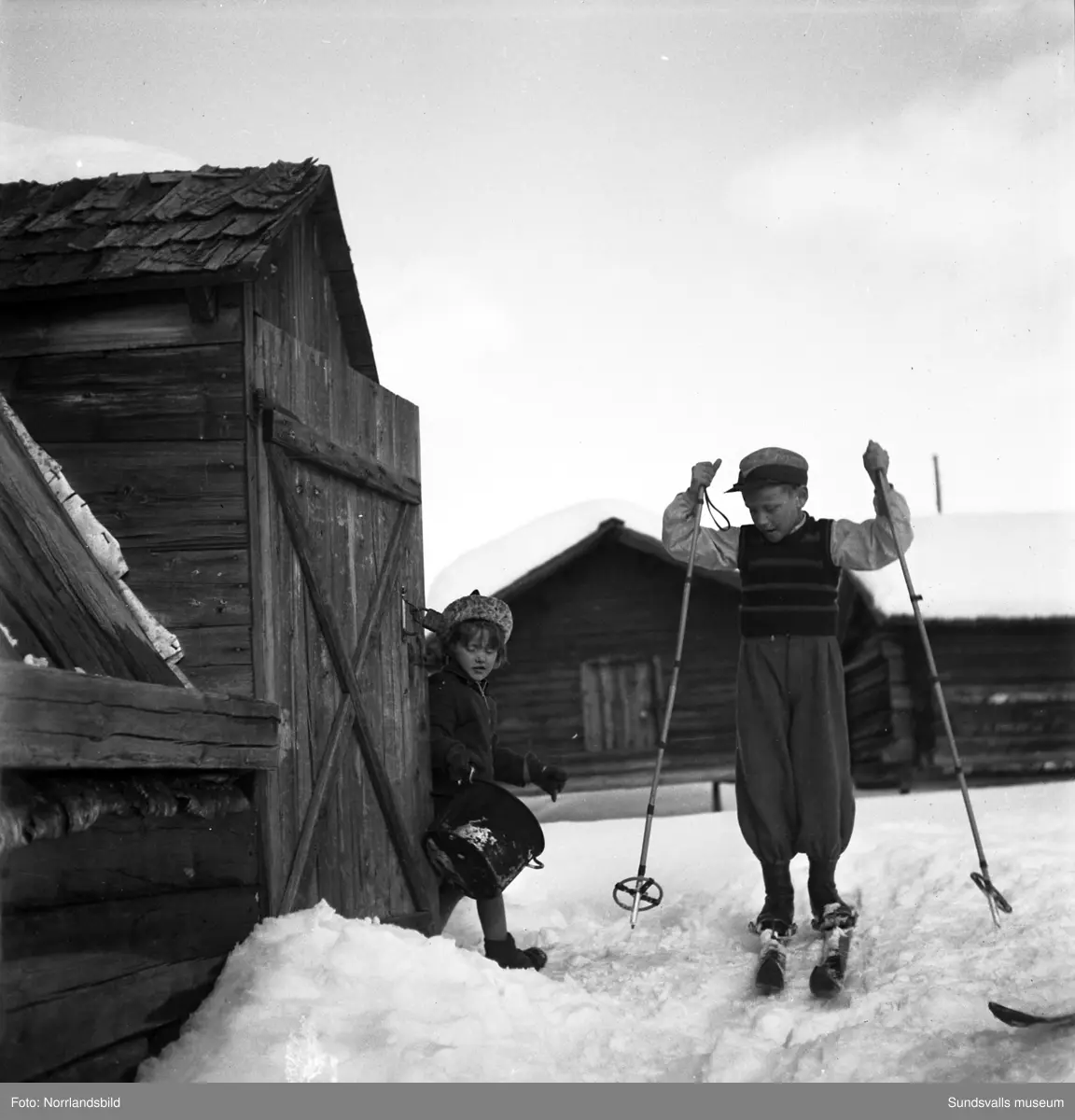 Vinterbilder från landsbygden, små stugor och uthus, barn som åker ...
