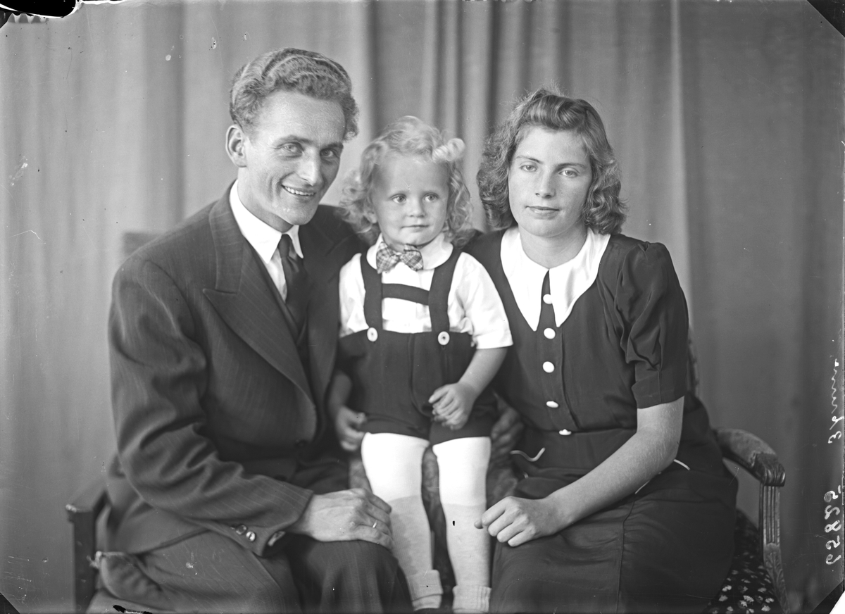 Gruppebilde. Familiegruppe på tre. Ung mann, ung gutt med langt lyst ...