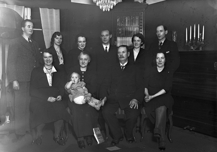 Foto av en familj med vuxna barn och ett barnbarn i ett vardagsrum ...