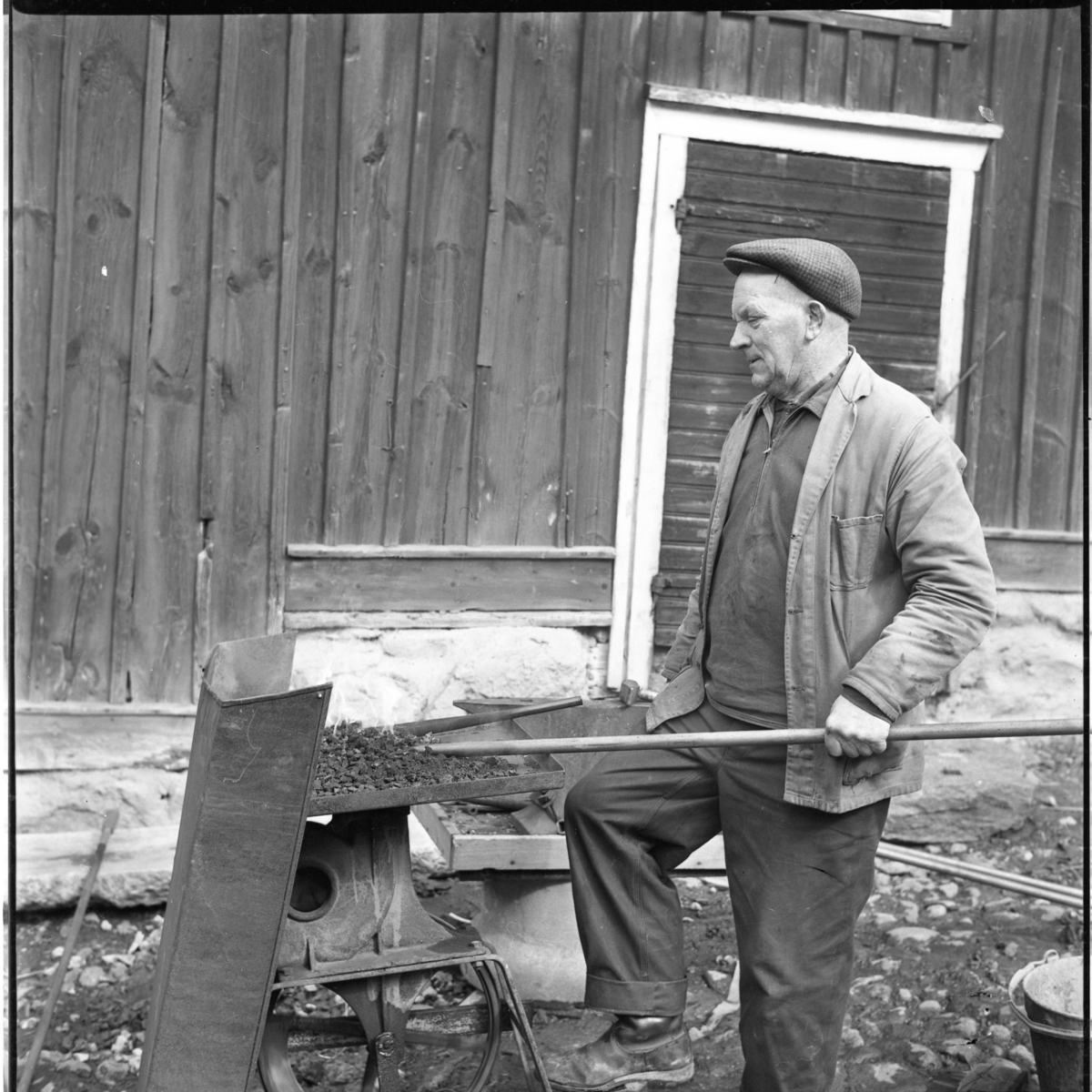 Carl Wall står och arbetar vid en mobil ässja utanför en ekonomibyggnad ...