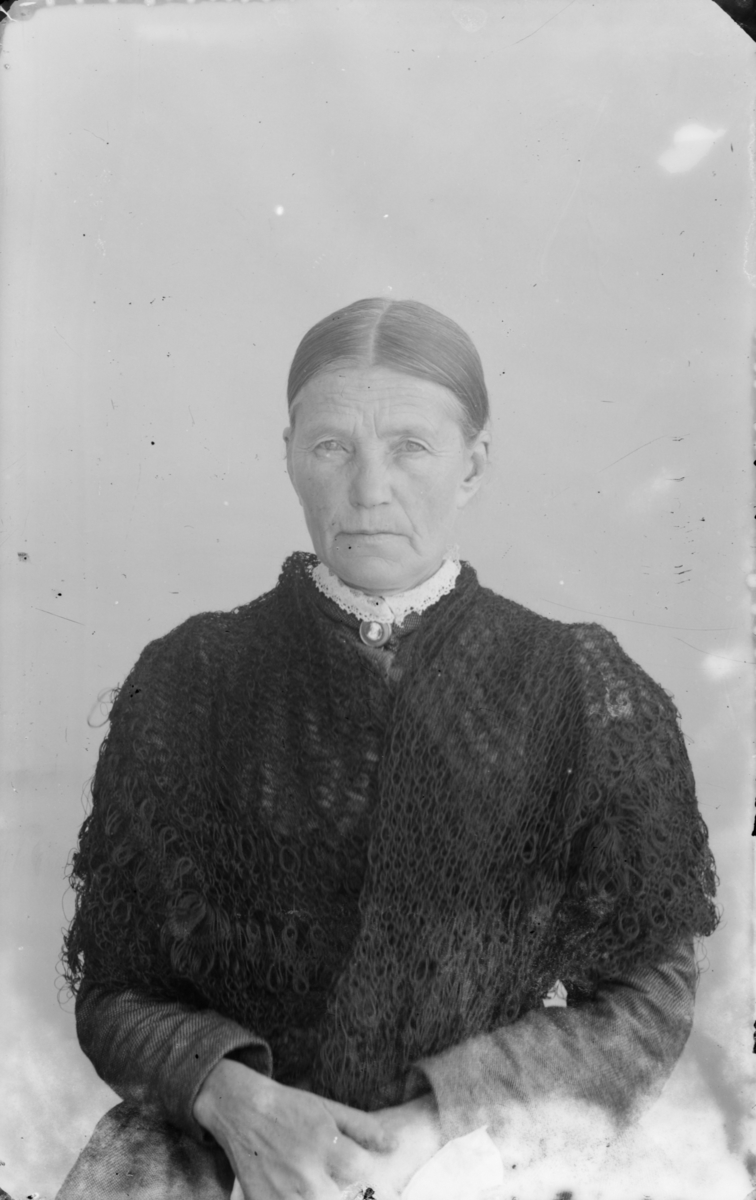 Portrett av eldre dame med midtskille i håret og heklet sjal over ...