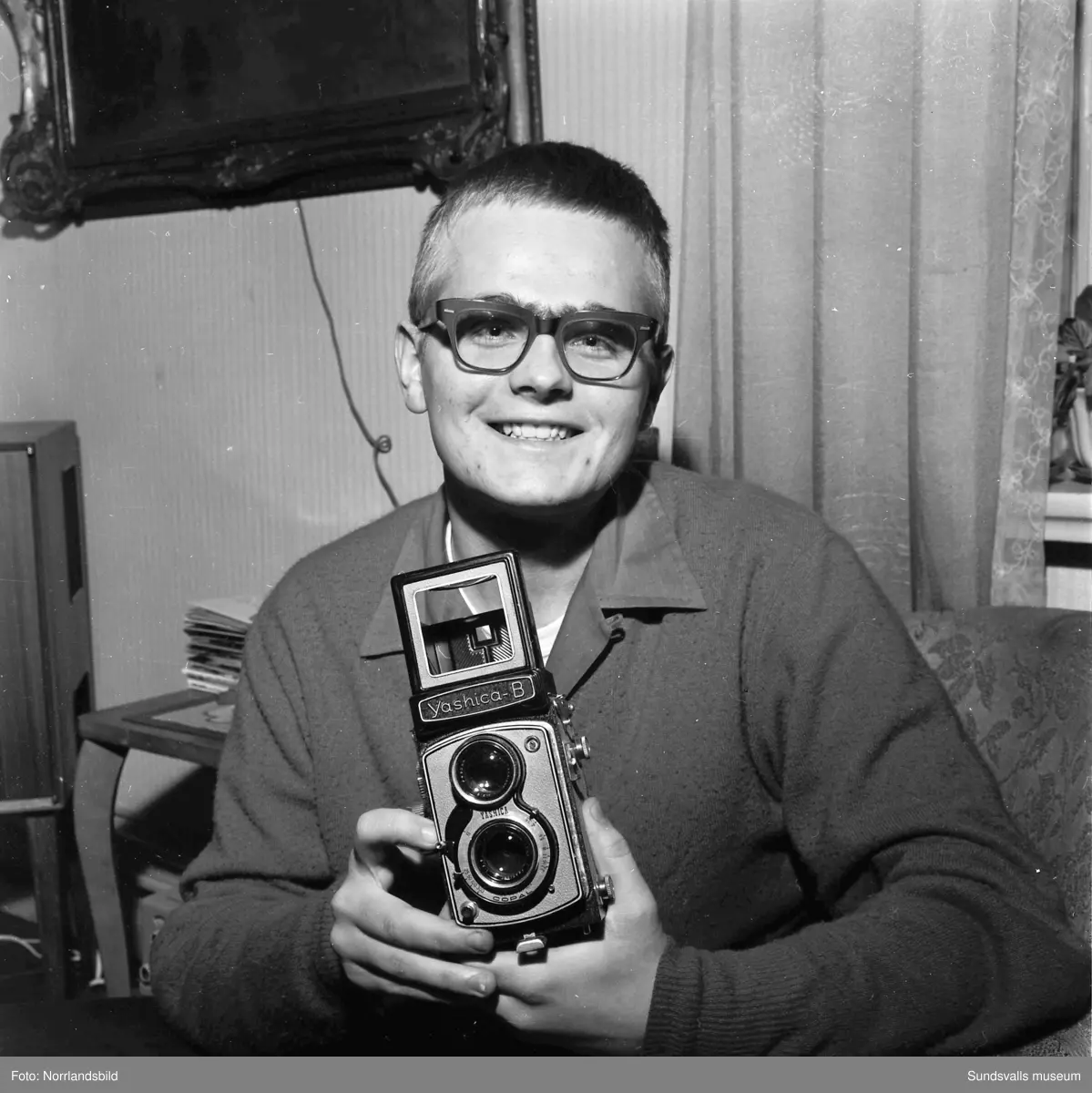 Porträttbild av Jan Bruér, med en kamera i händerna. - Sundsvalls ...
