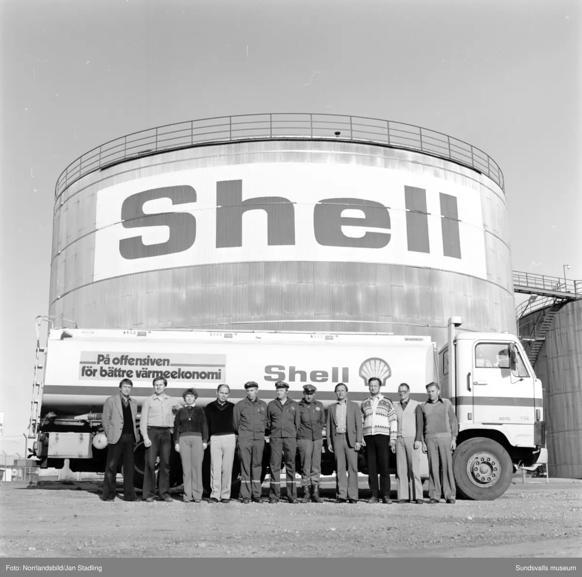 Gruppbild av personal på Shell framför företagets oljecistern och ...